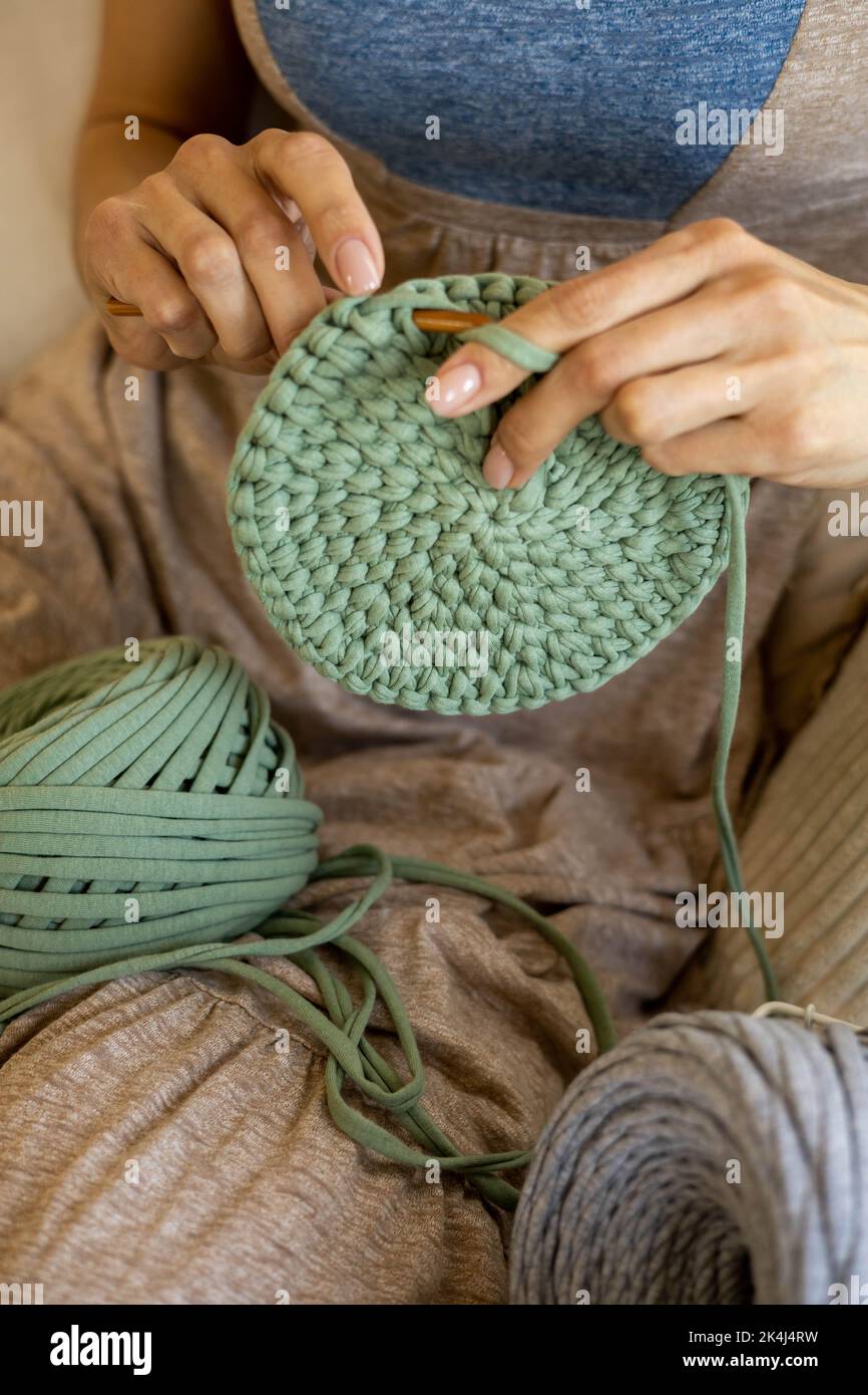 Closeup female hands knitting interior decor basket use green ribbon ...