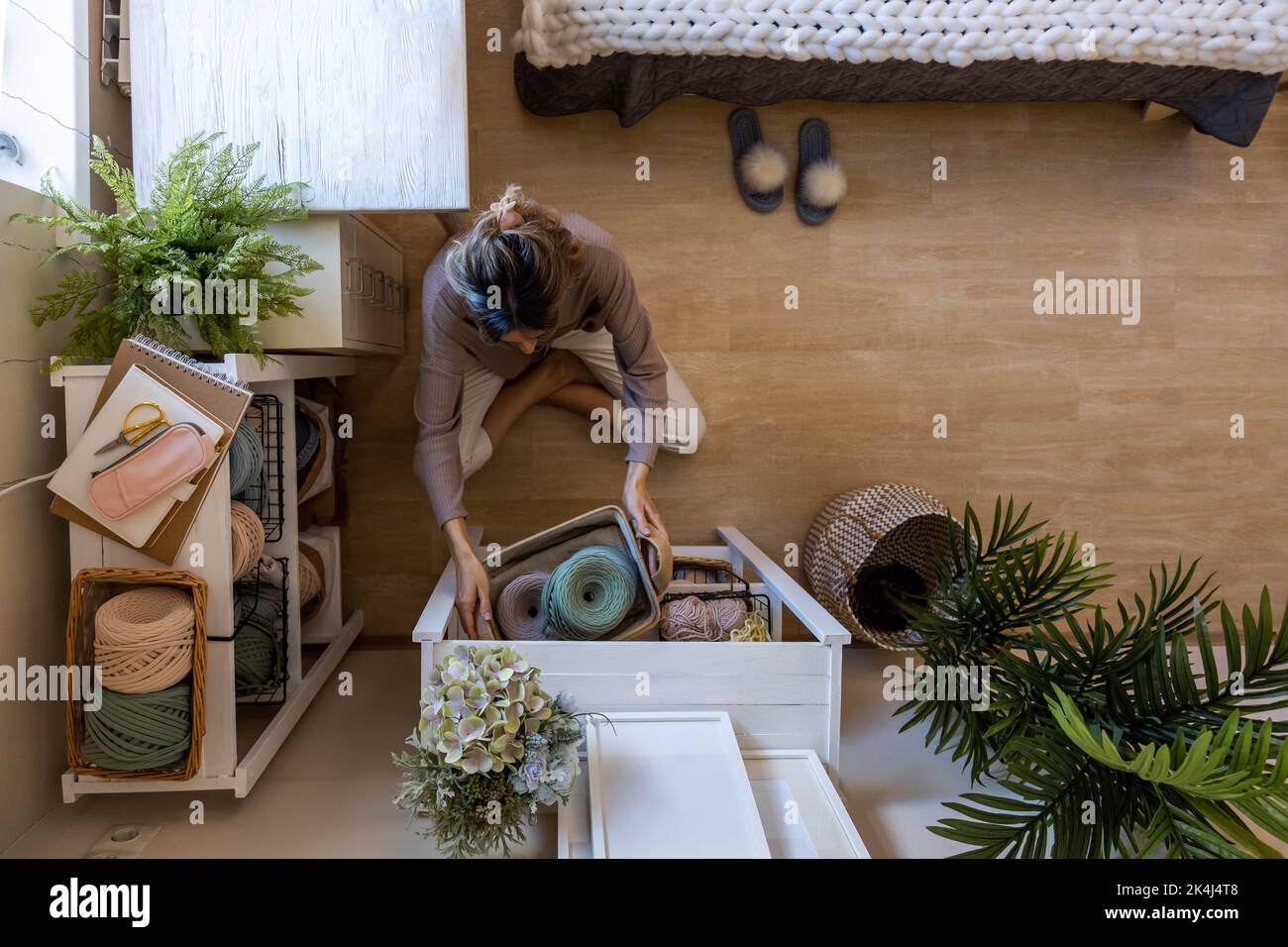 Top view woman knitted clothes designer tidying up ribbon yarn needles ...