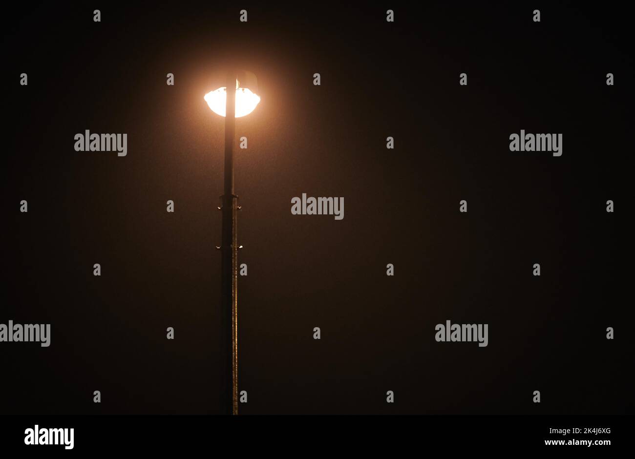 One night lamppost shines with faint mysterious yellow light through ...