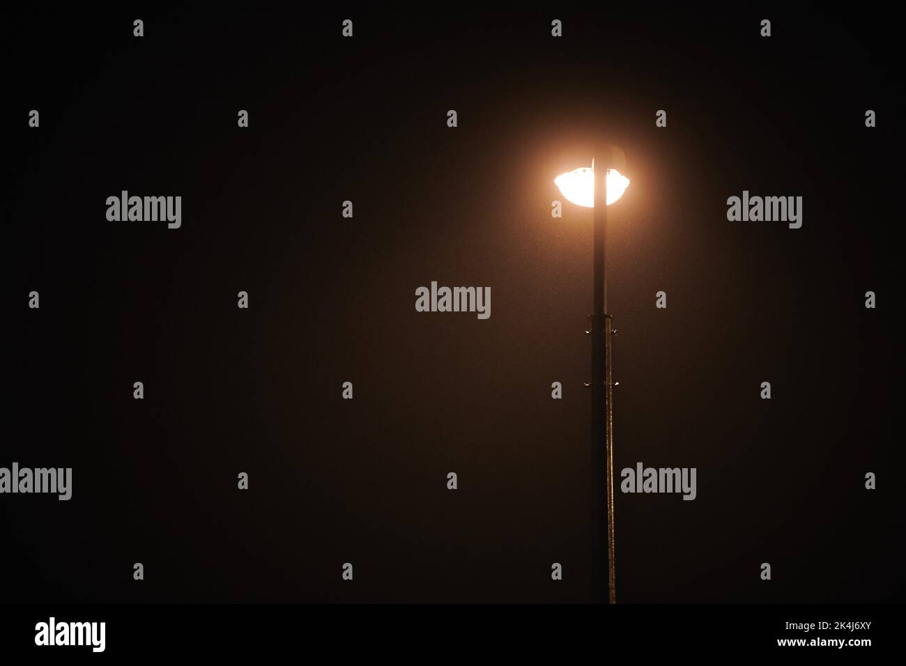 One night lamppost shines with faint mysterious yellow light through ...