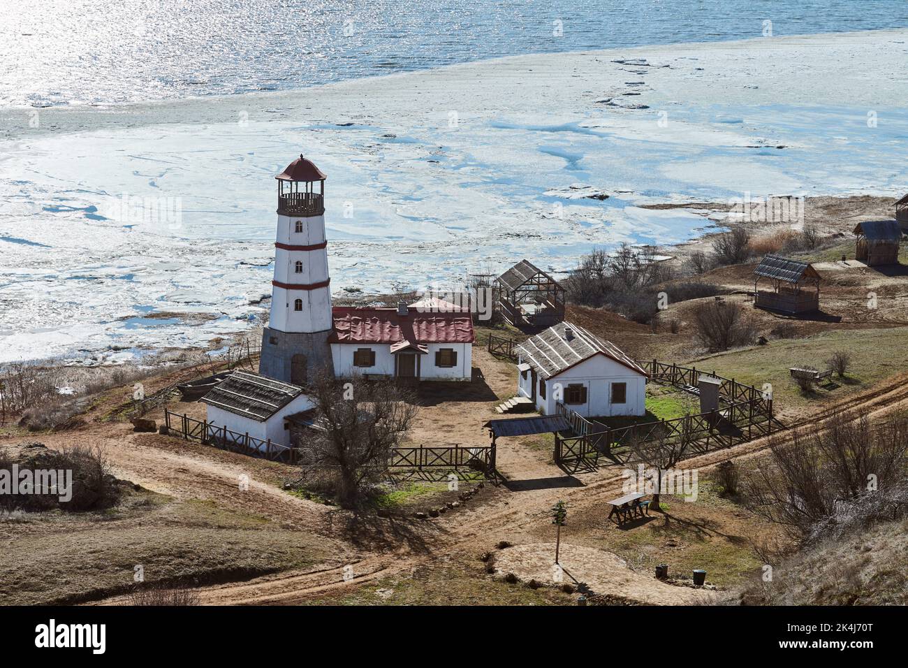 Beautiful white red lighthouse with farm utility houses in Merzhanovo ...