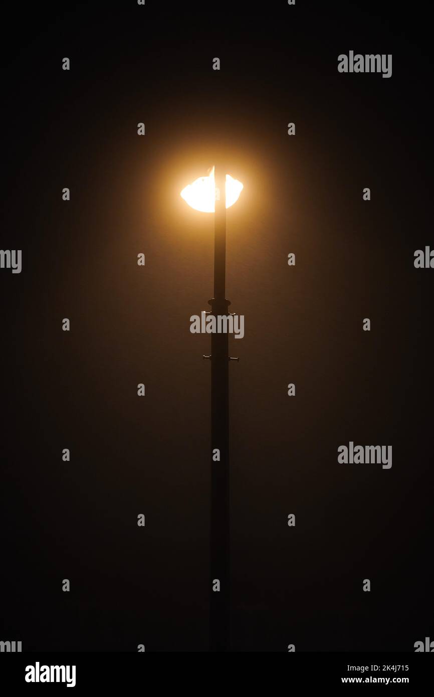 One night lamppost shines with faint mysterious yellow light through ...