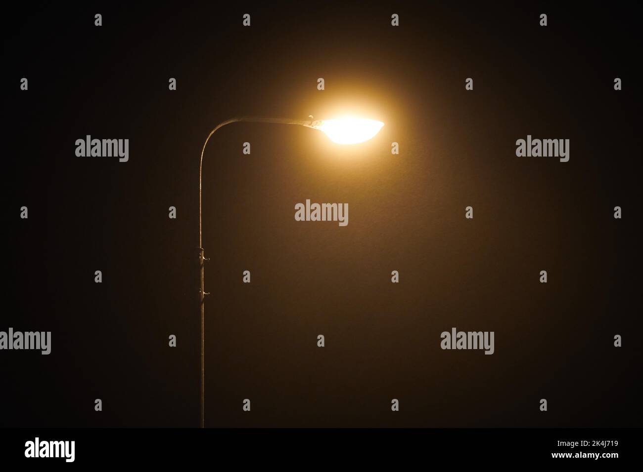 One night lamppost shines with faint mysterious yellow light through ...