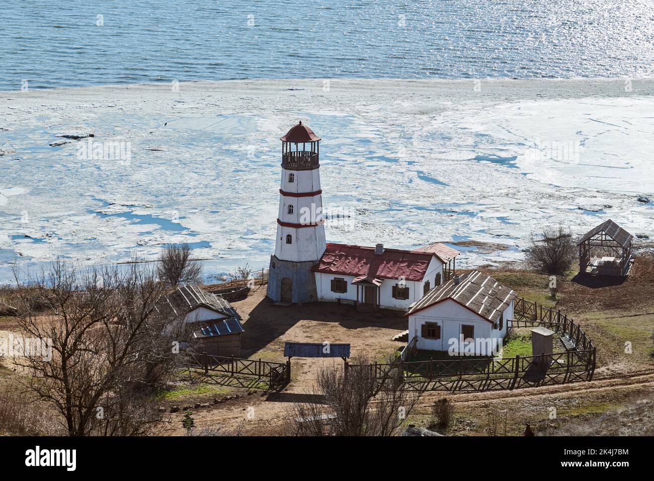 Beautiful white red lighthouse with farm utility houses in Merzhanovo ...