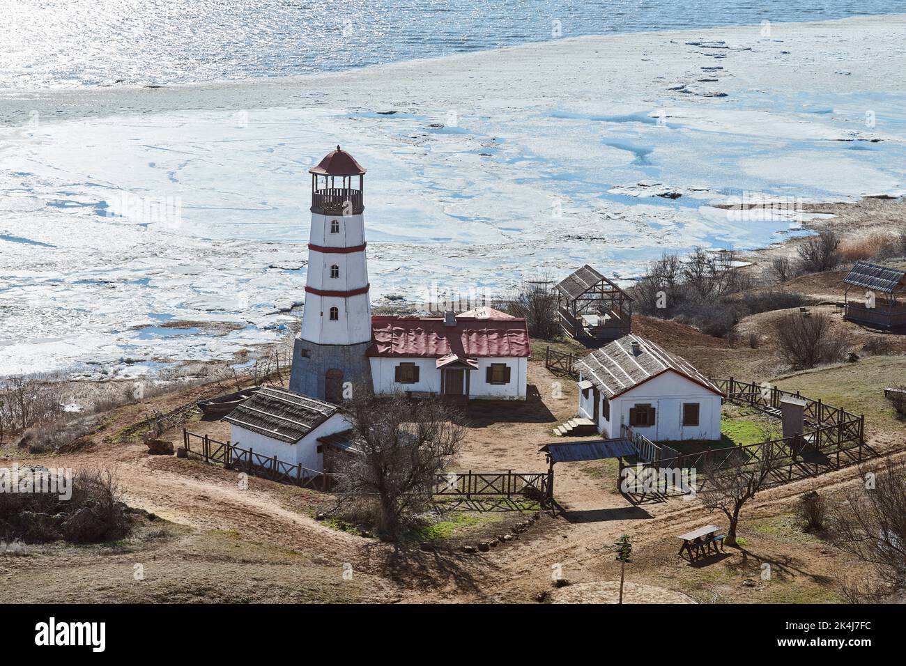 Beautiful white red lighthouse with farm utility houses in Merzhanovo ...