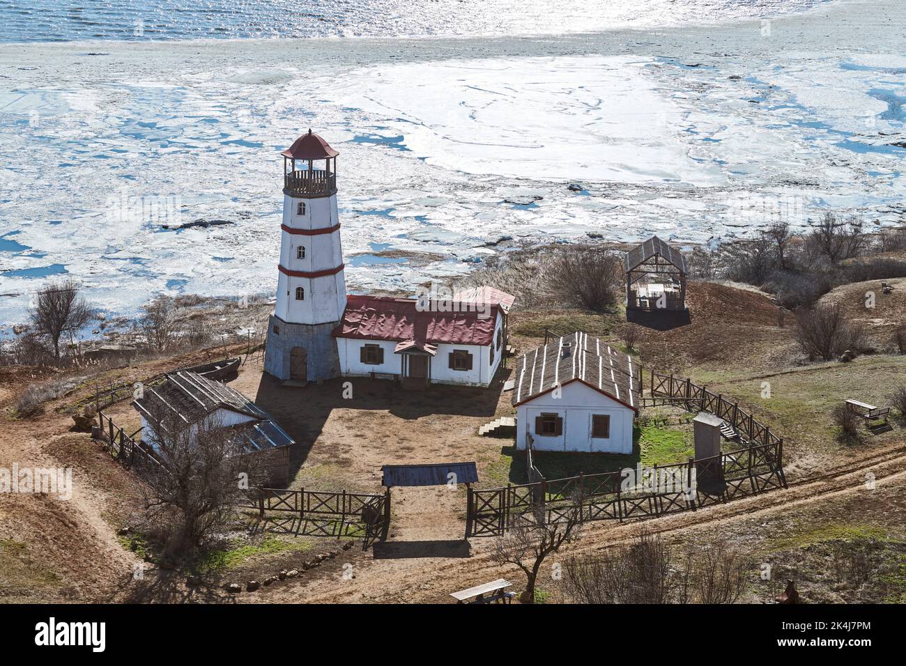 Beautiful white red lighthouse with farm utility houses in Merzhanovo ...