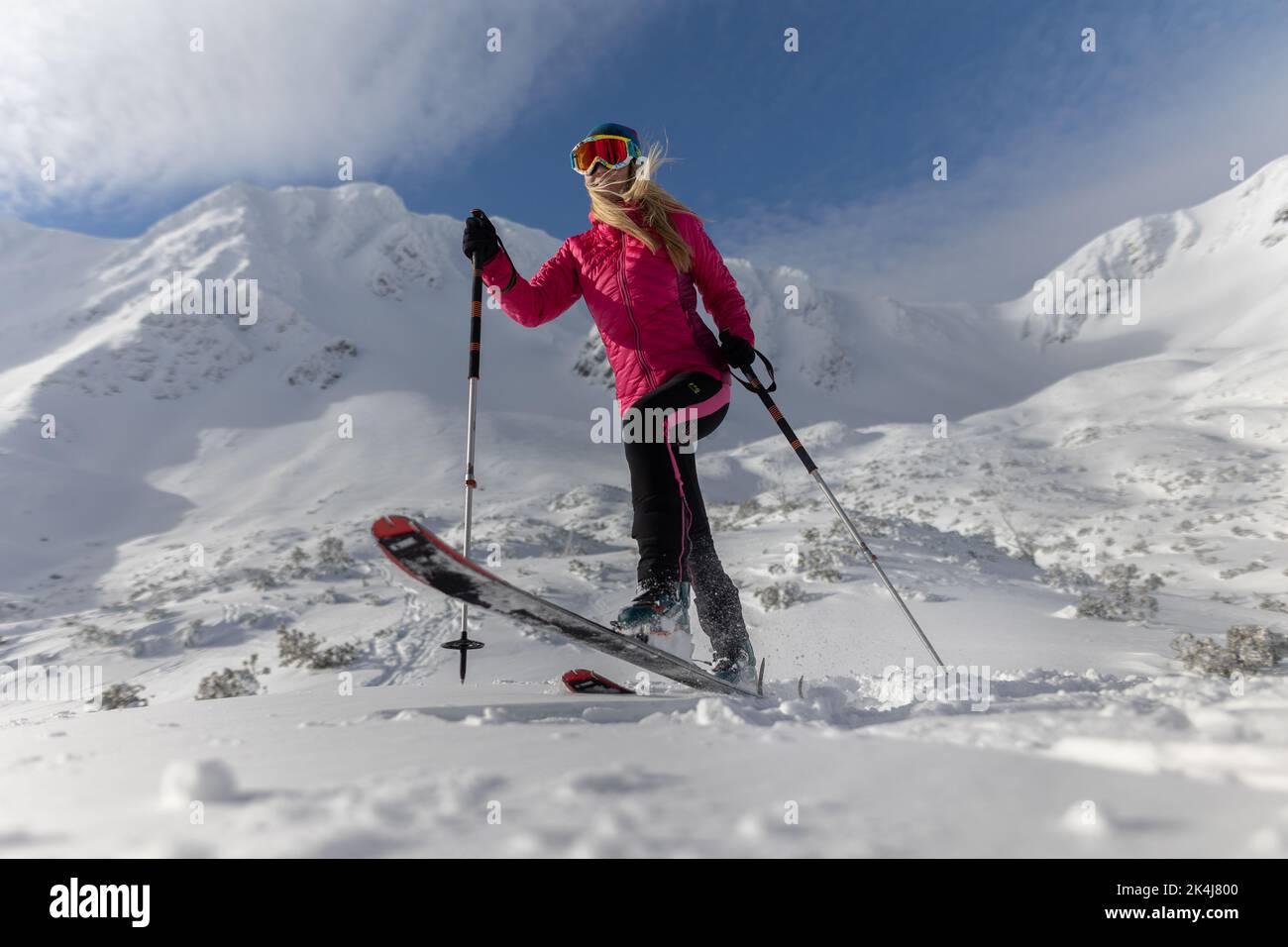 Female backcountry skier hiking to the summit of a snowy peak in the ...