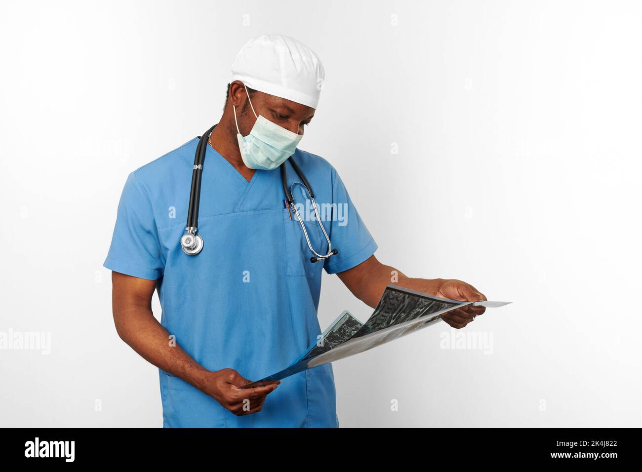 Black surgeon doctor man in blue coat white cap and surgeon mask holds ...