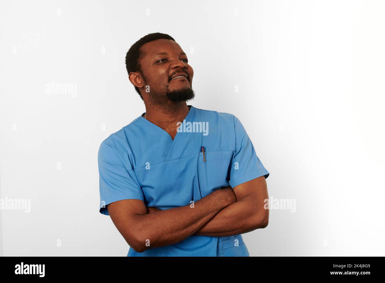 Smiling black surgeon doctor bearded man in blue coat with crossed arms ...