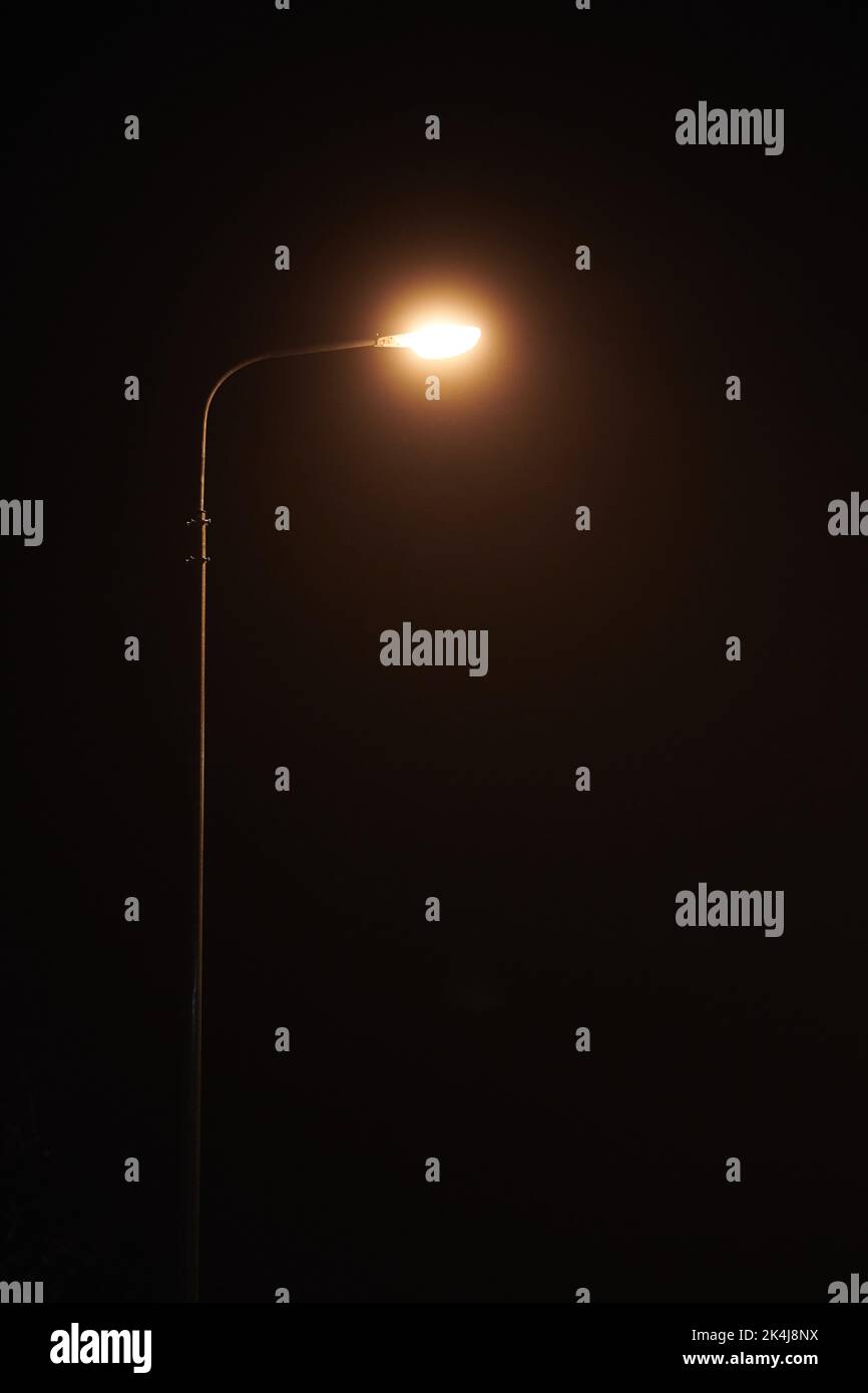 One night lamppost shines with faint mysterious yellow light through ...