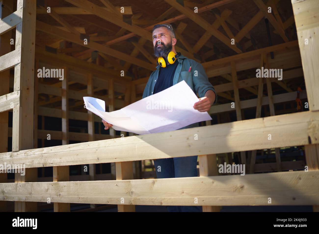 Handyman chcecking blueprints and working on wooden construction site ...