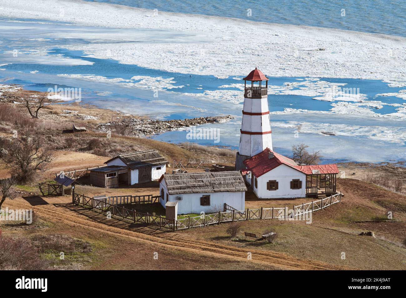 Beautiful white red lighthouse with farm utility houses in Merzhanovo ...