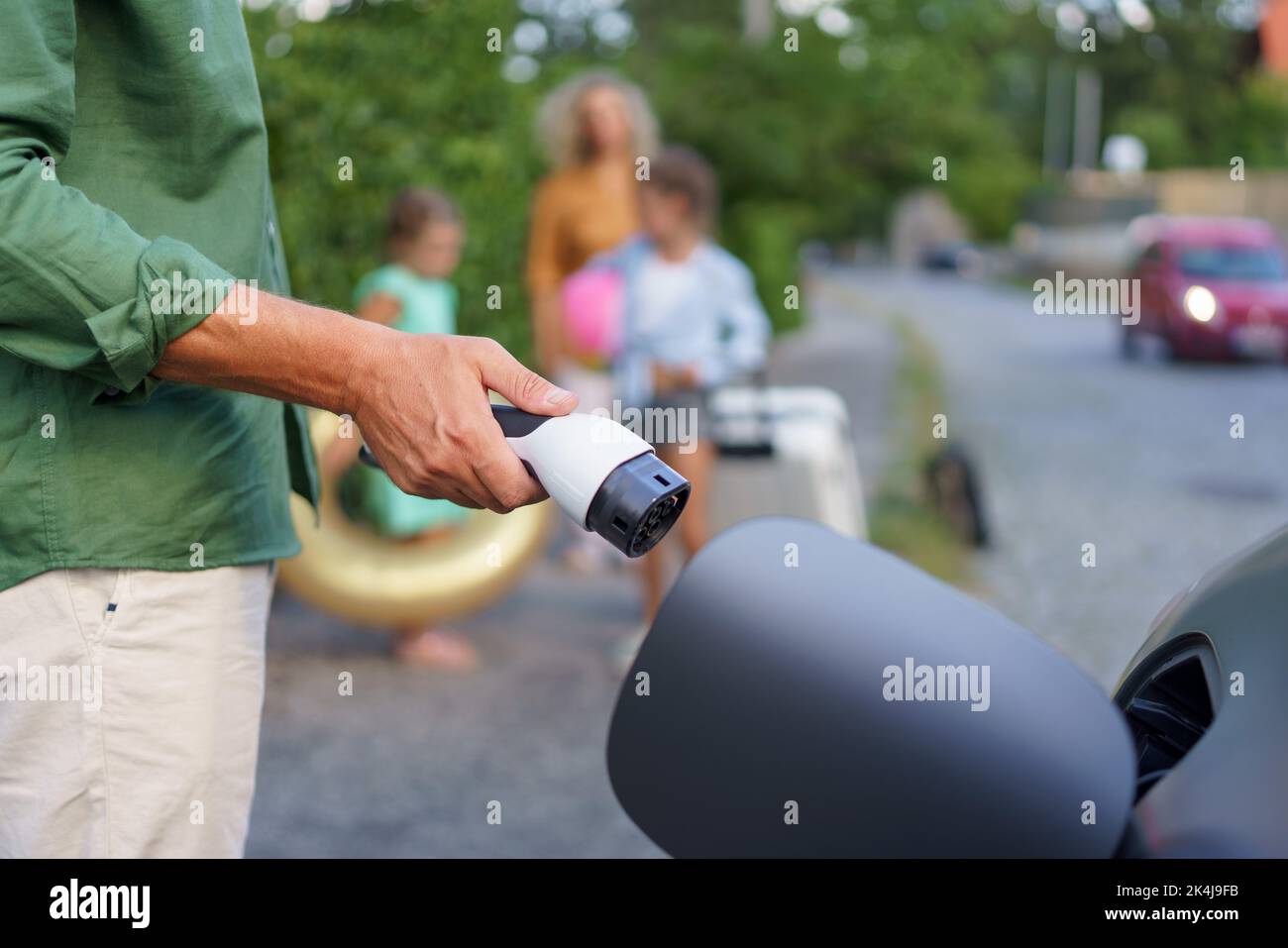 Man holding power supply cable, while his family waiting for car ...