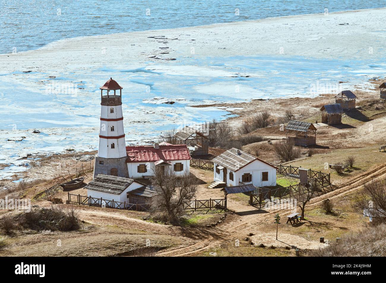Beautiful white red lighthouse with farm utility houses in Merzhanovo ...