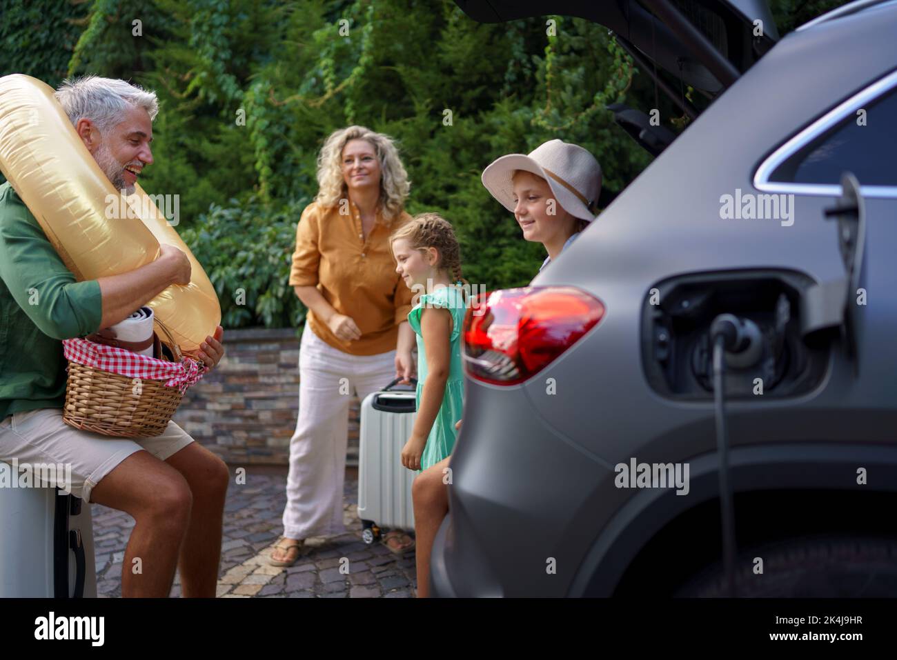 Family with little children loading car and waiting for charging car ...