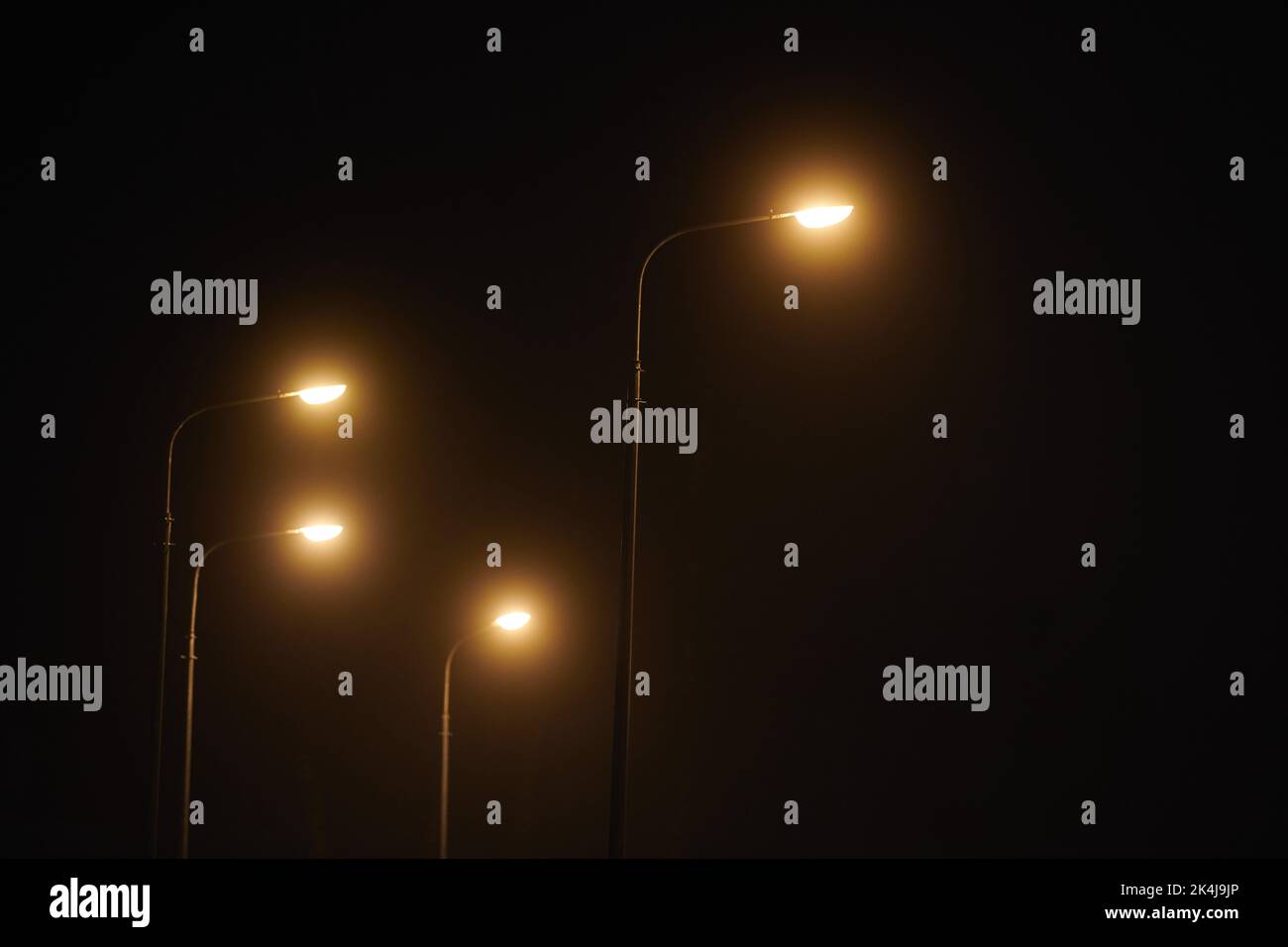 Night lampposts shines with faint mysterious yellow light through ...