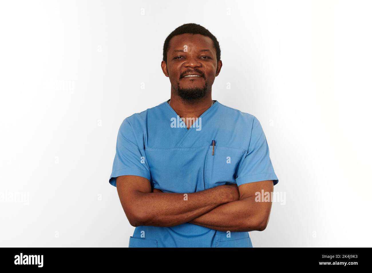 Smiling black surgeon doctor bearded man in blue coat with crossed arms ...