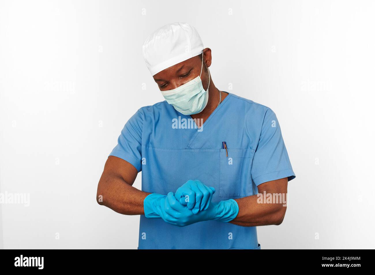 Black surgeon doctor man in blue coat white cap surgeon mask sterilizes ...