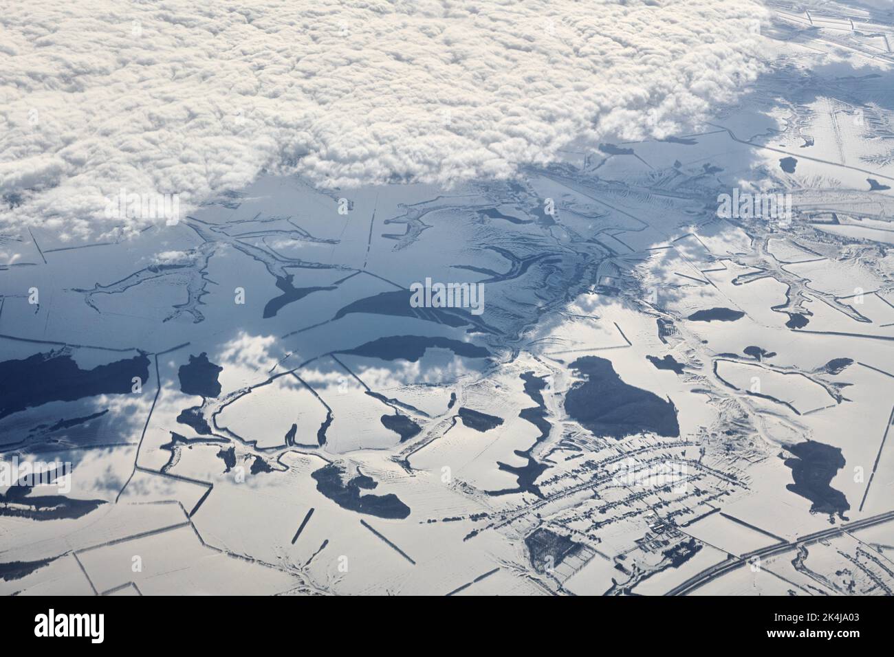 Aerial cloudscape view over top clouds to snow covered rivers, roads ...