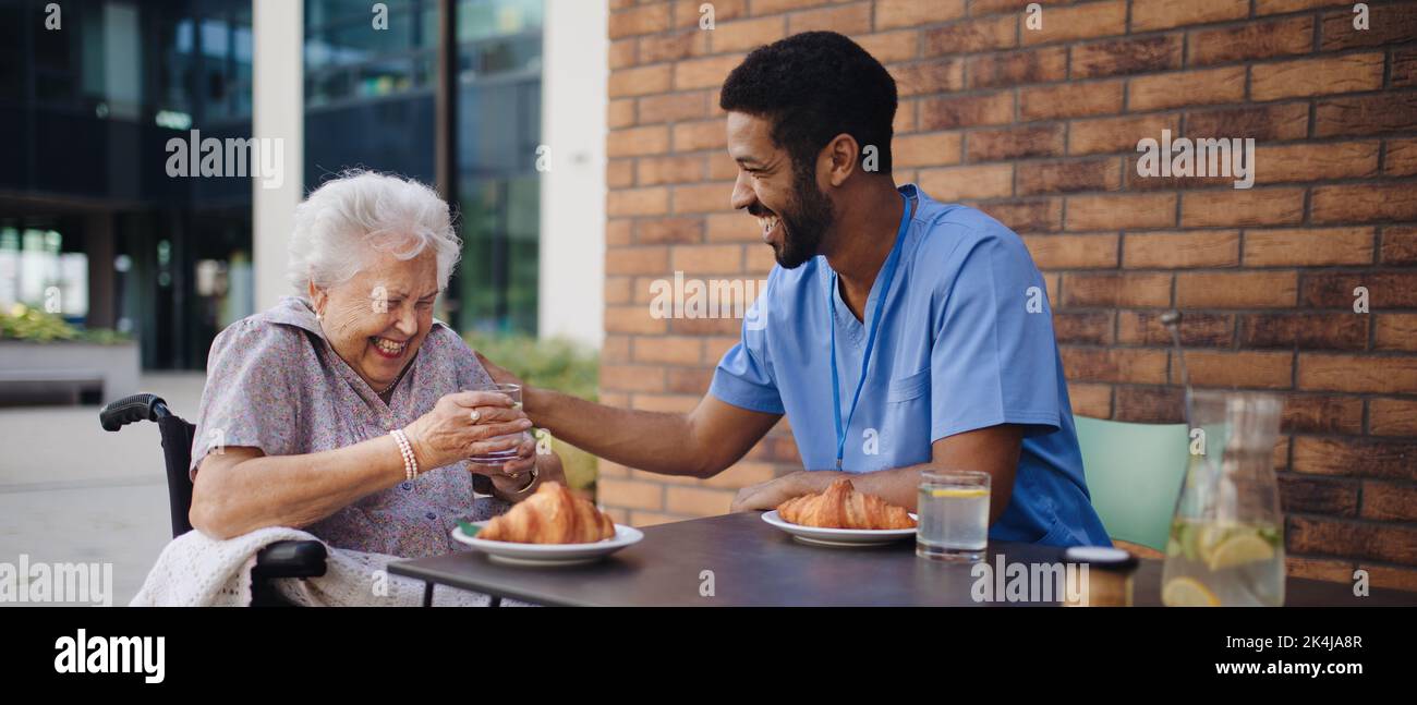 Caregiver having breakfast with his client at a cafe Stock Photo - Alamy