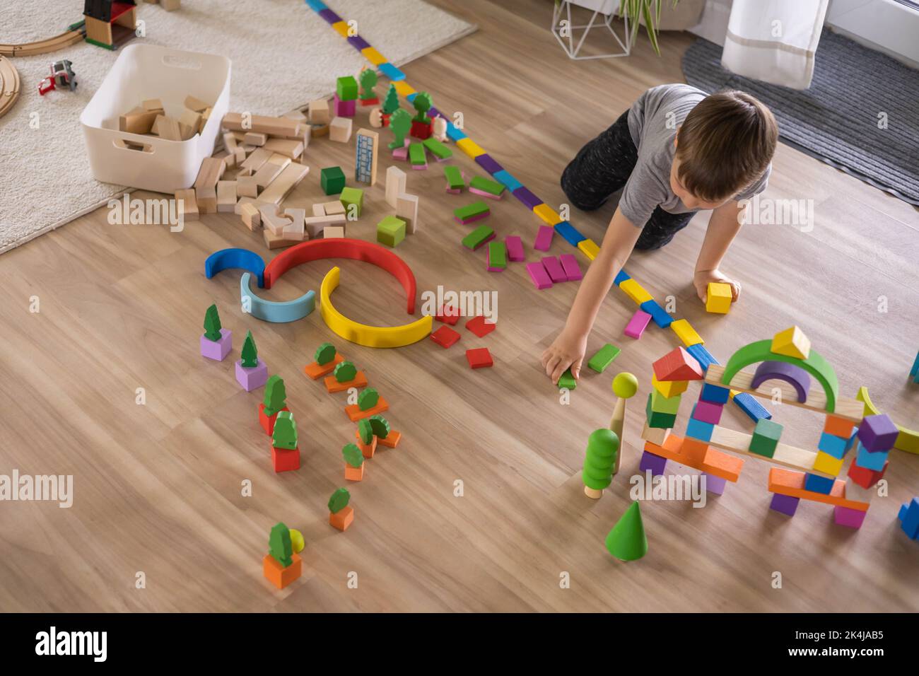 Confident male kid building fortress tower architecture wooden bricks ...