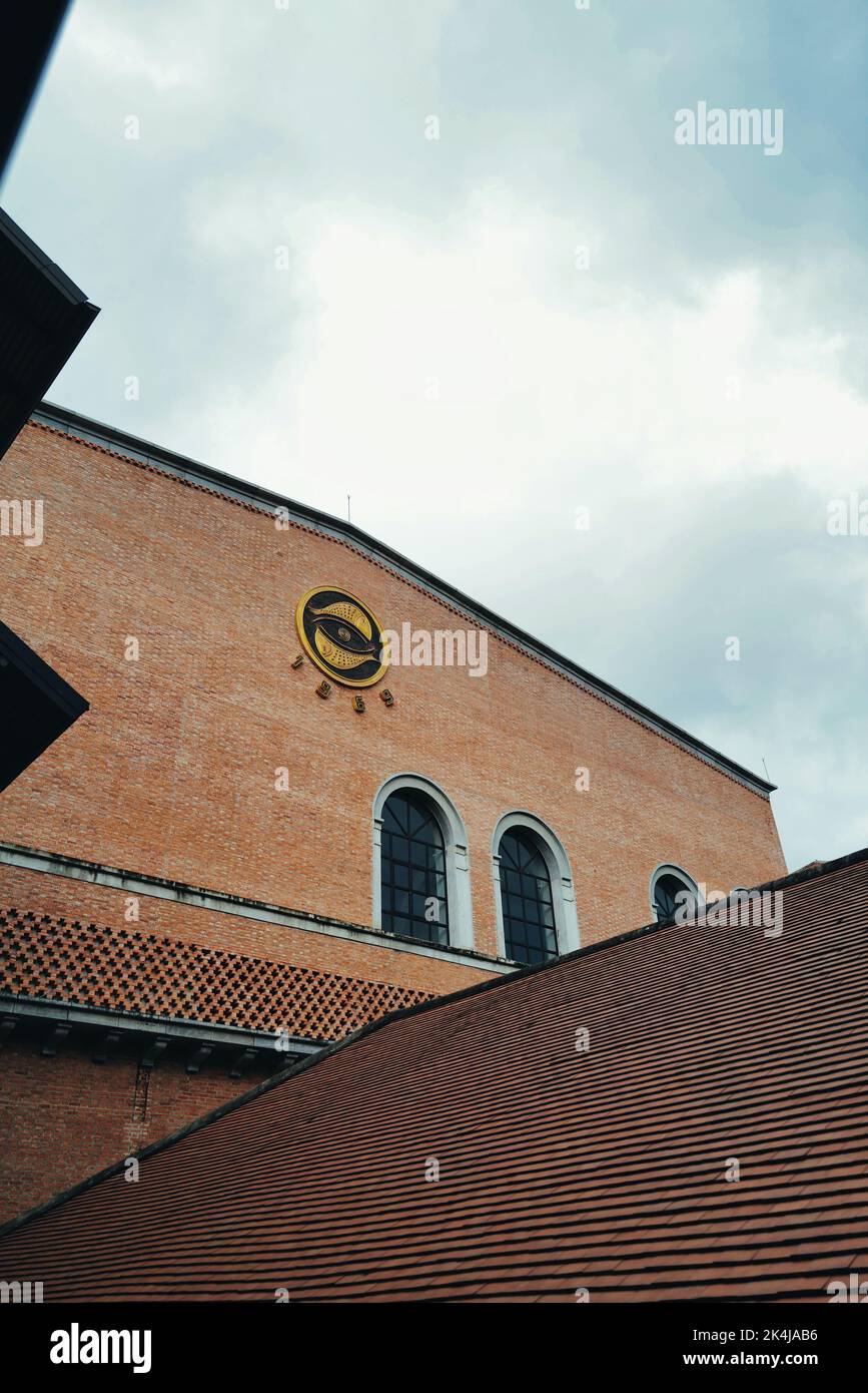 A vertical shot of an old brick building with an emblem of two golden ...