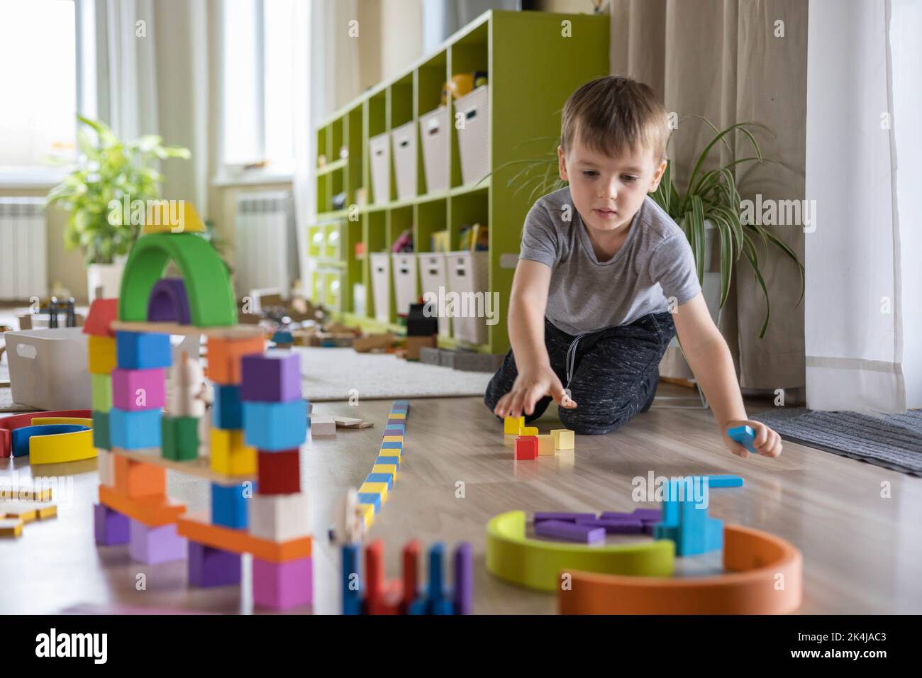 Confident male kid building fortress tower architecture wooden bricks ...