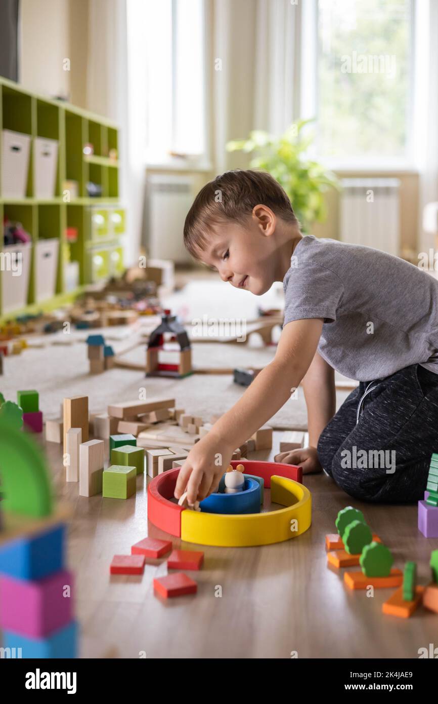Confident male kid building fortress tower architecture wooden bricks ...