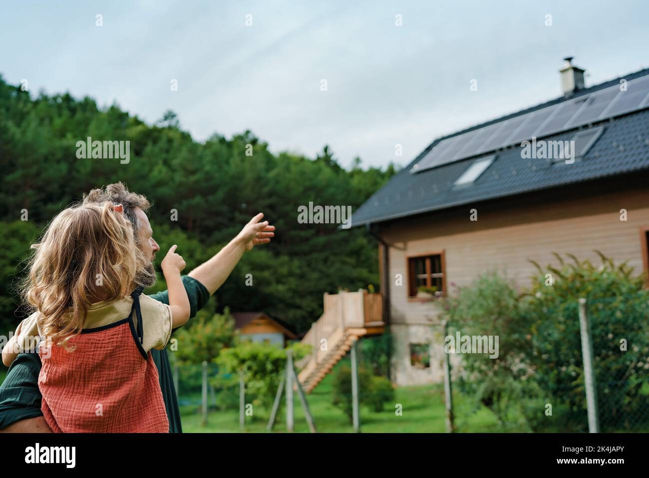 Rear view of dad holding her little girl in arms and showing at their ...