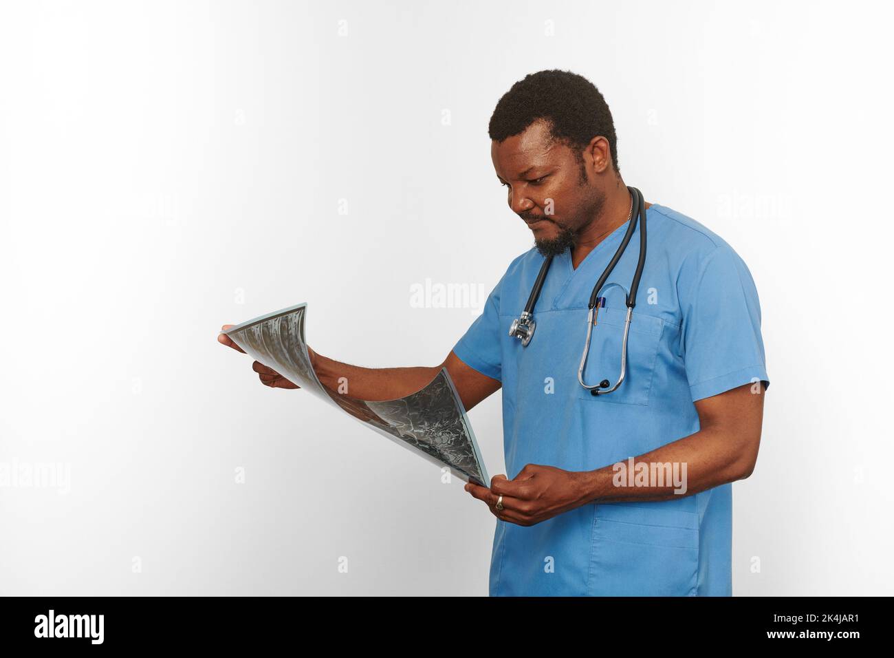 Black surgeon doctor bearded man in blue coat with stethoscope holds X ...