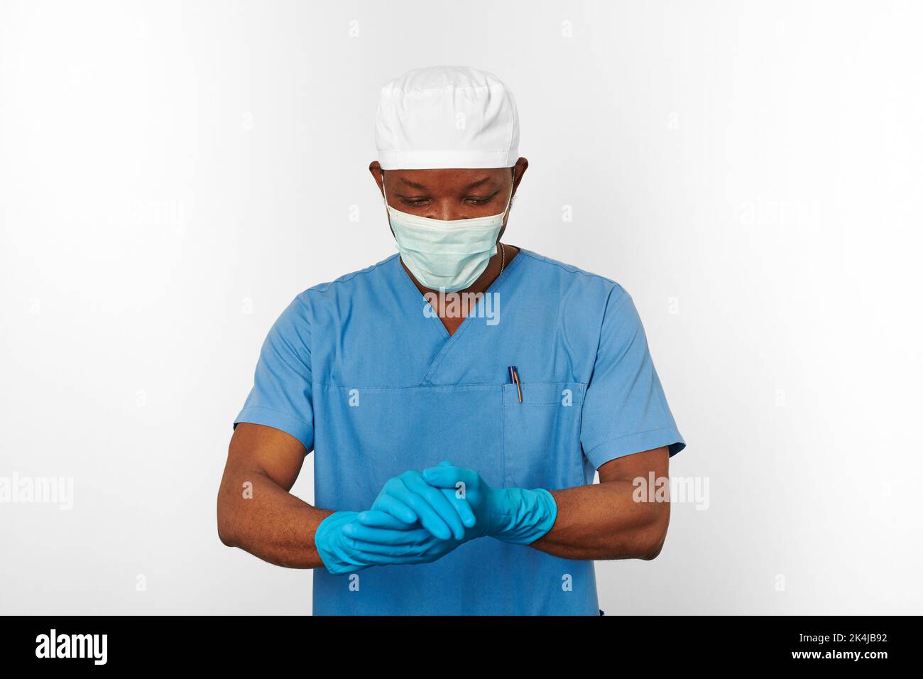 Black surgeon doctor man in blue coat white cap surgeon mask sterilizes ...
