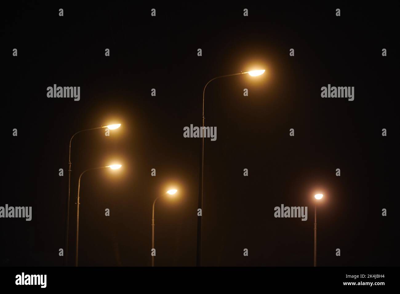 Night lampposts shines with faint mysterious yellow light through ...