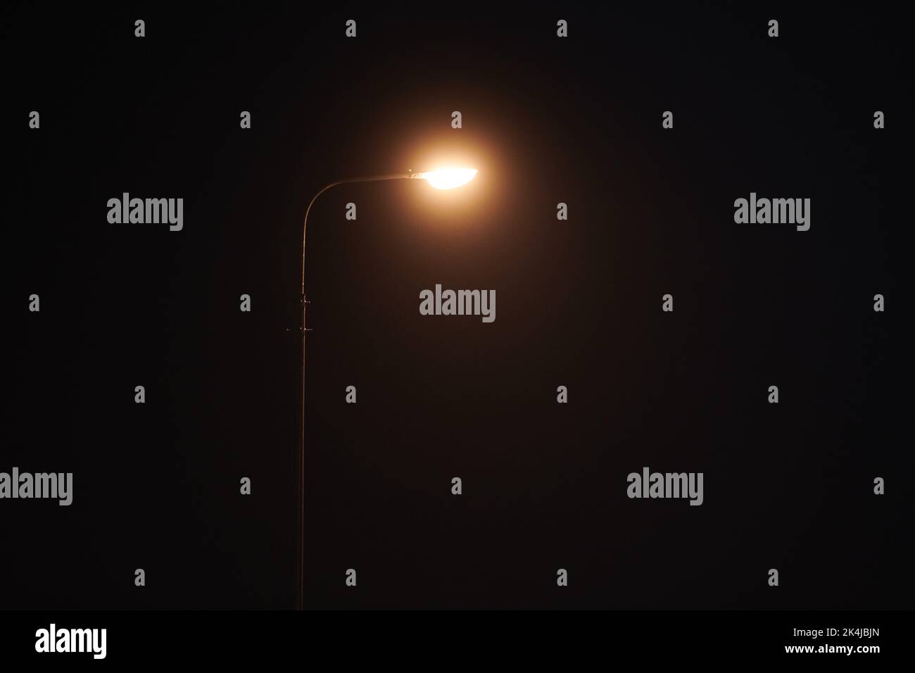 One night lamppost shines with faint mysterious yellow light through ...