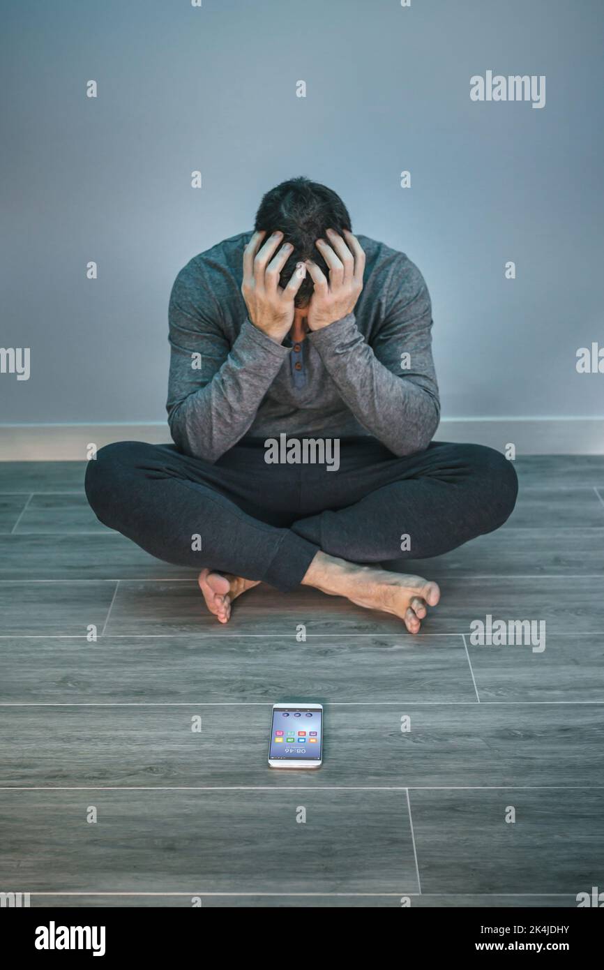 Man with problems sitting on the floor behind of his mobile Stock Photo ...