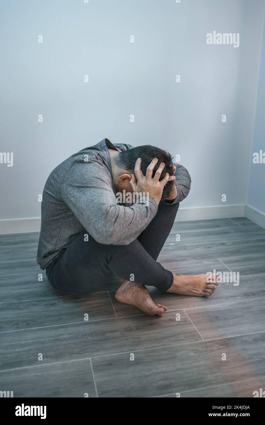Unrecognizable man with problems sitting on the floor Stock Photo - Alamy