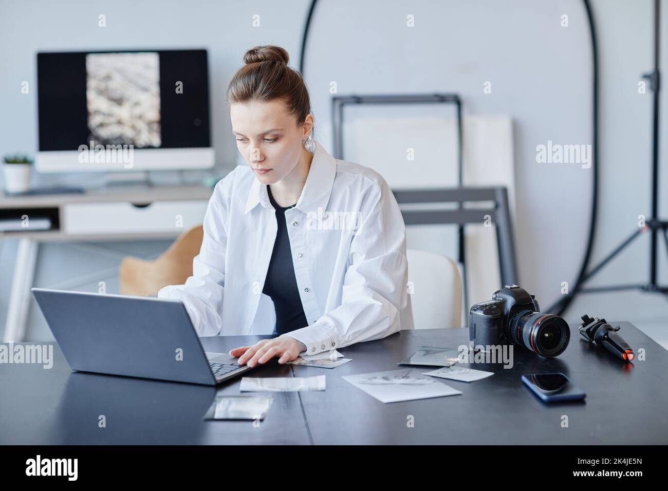 Portrait of young female photographer using laptop for retouch and ...