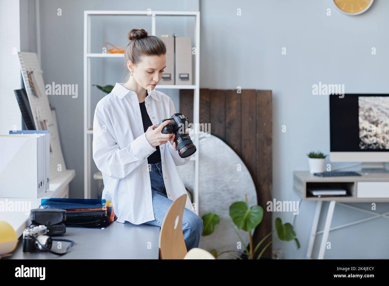Portrait of young female photographer looking at camera images in ...