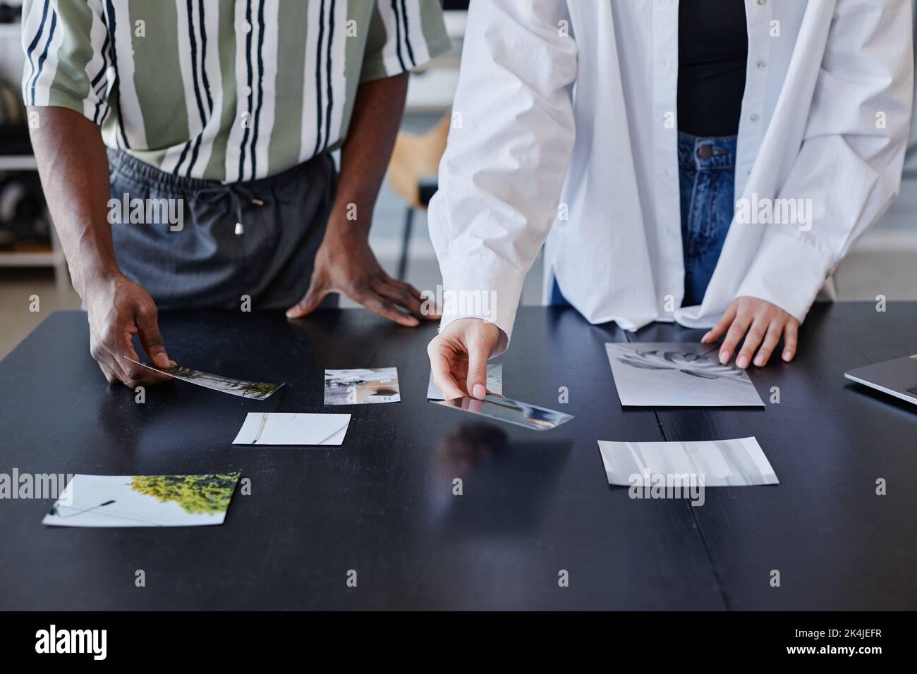Close up of two photographers laying out printed images on table and ...