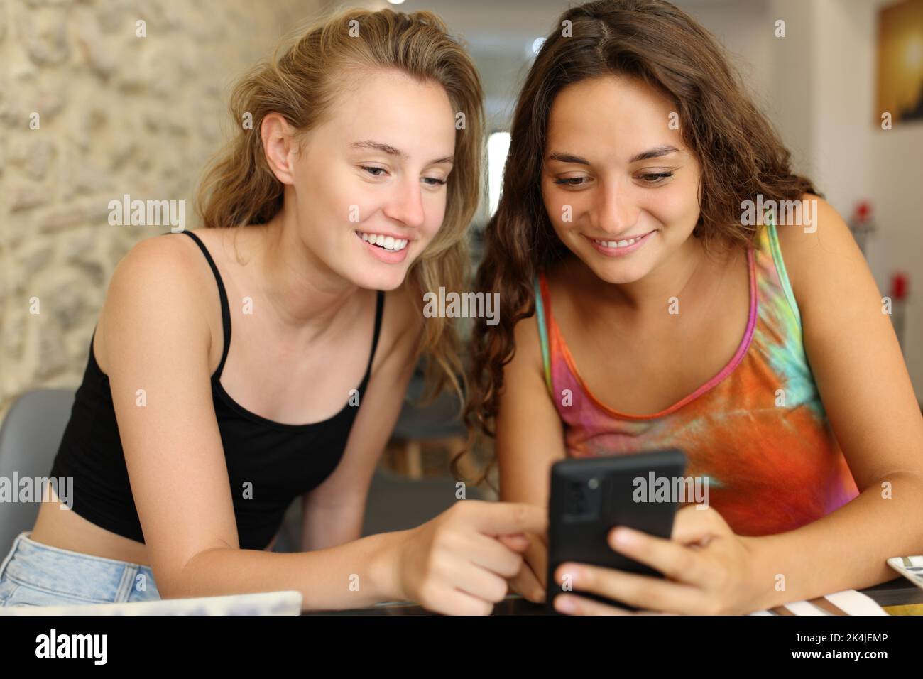 Two happy friends checking phone together in a restaurant Stock Photo ...