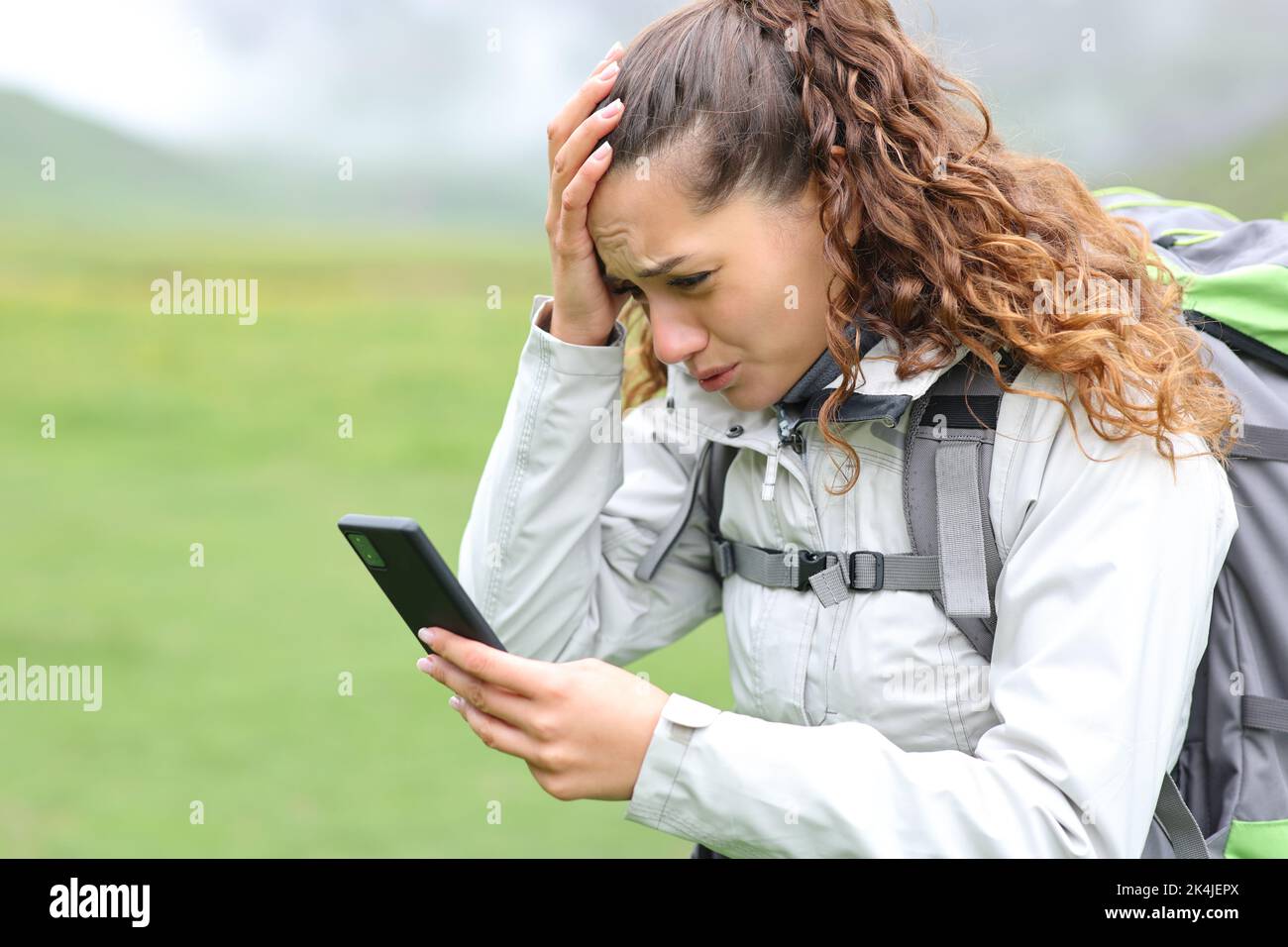 Worried hiker checking smart phone news or gps location in the mountain ...