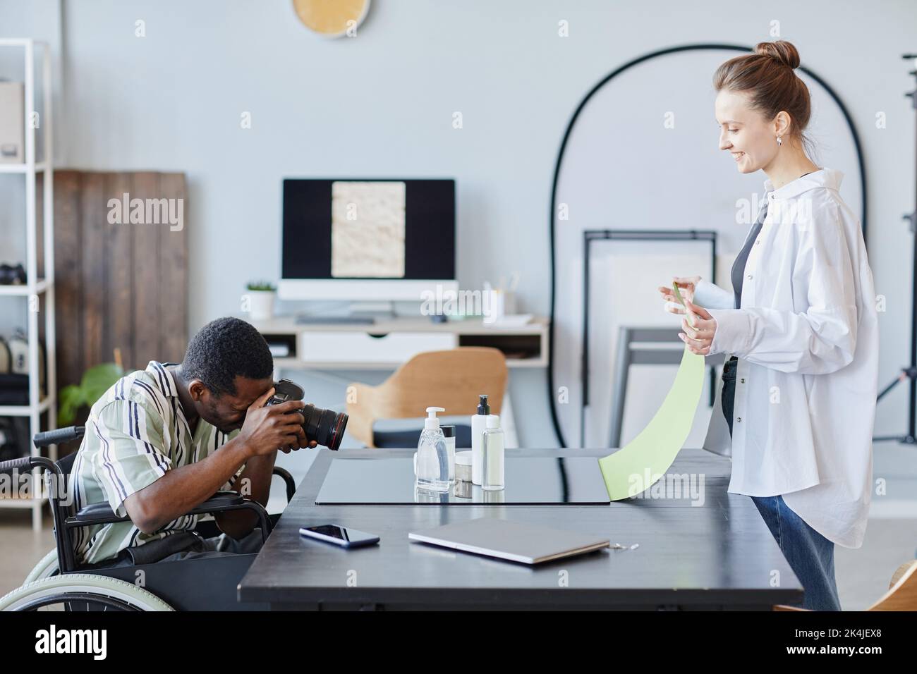 Side view portrait of young black man with disability as photographer ...