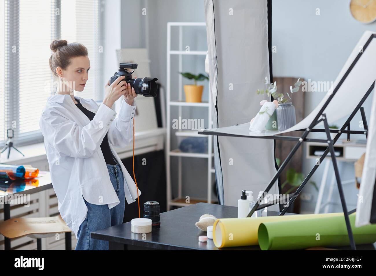 Side view portrait of woman pro photographer taking product image in ...