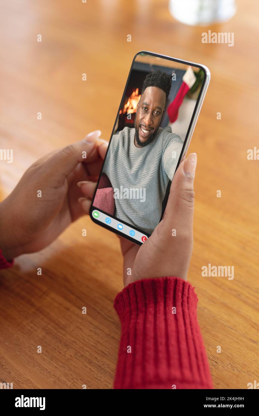 Hands holding smartphone with smiling african american man on christmas ...