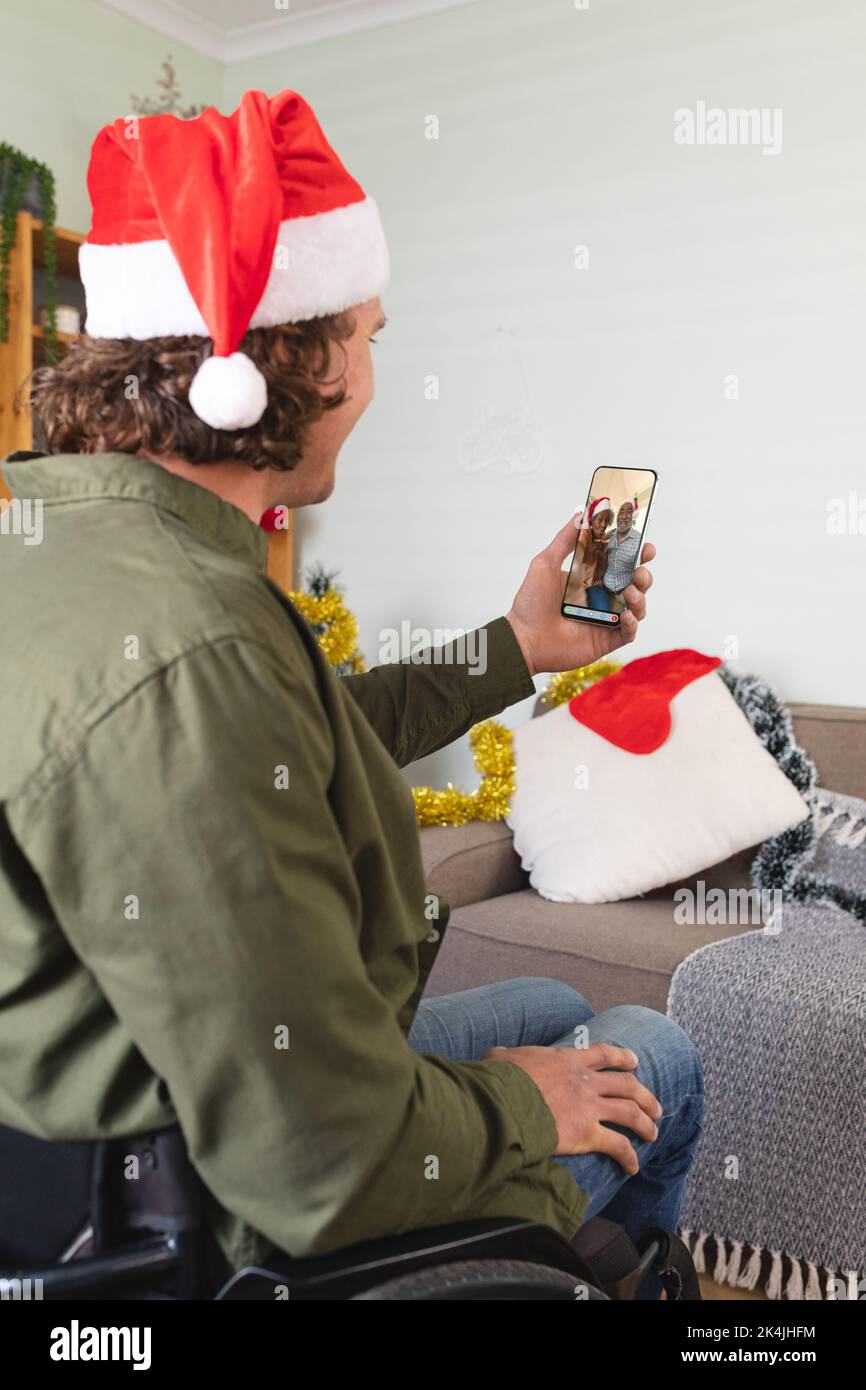 Caucasian man in wheelchair making smartphone christmas video call with ...