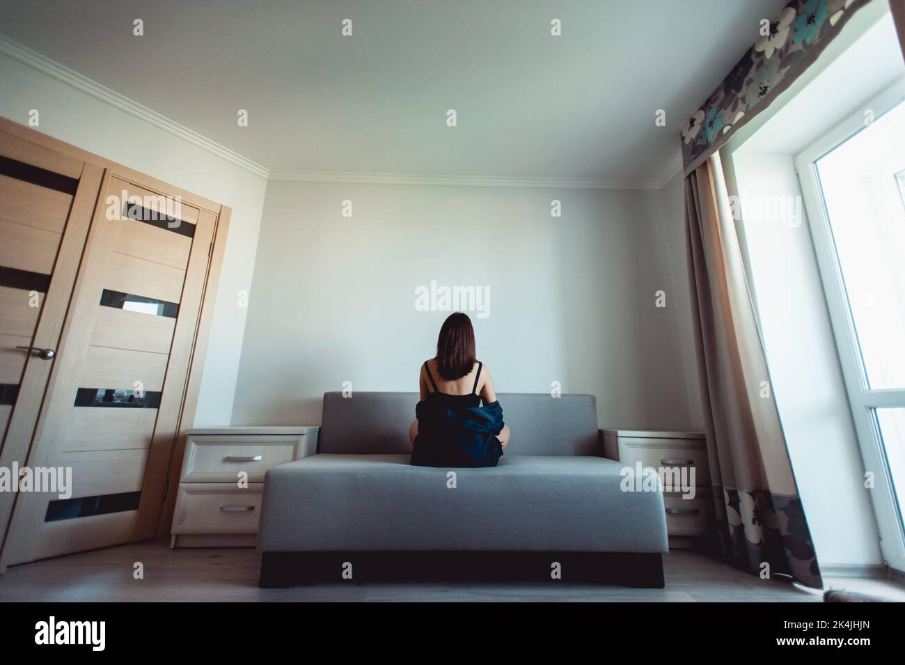 Loneliness. Alienation. Girl in an empty room sits back on a couch and ...
