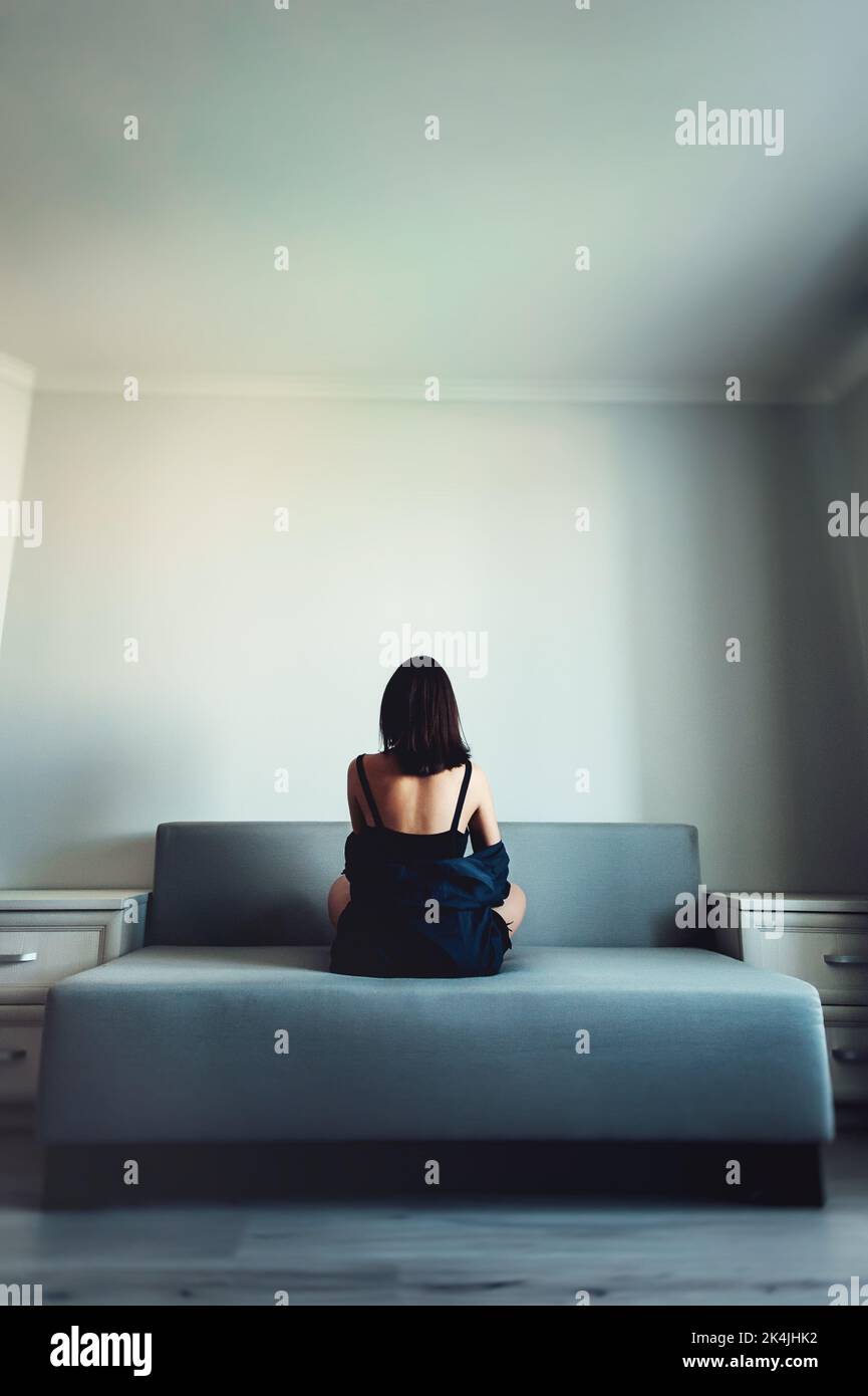 Loneliness. Alienation. Girl in an empty room sits back on a couch and ...