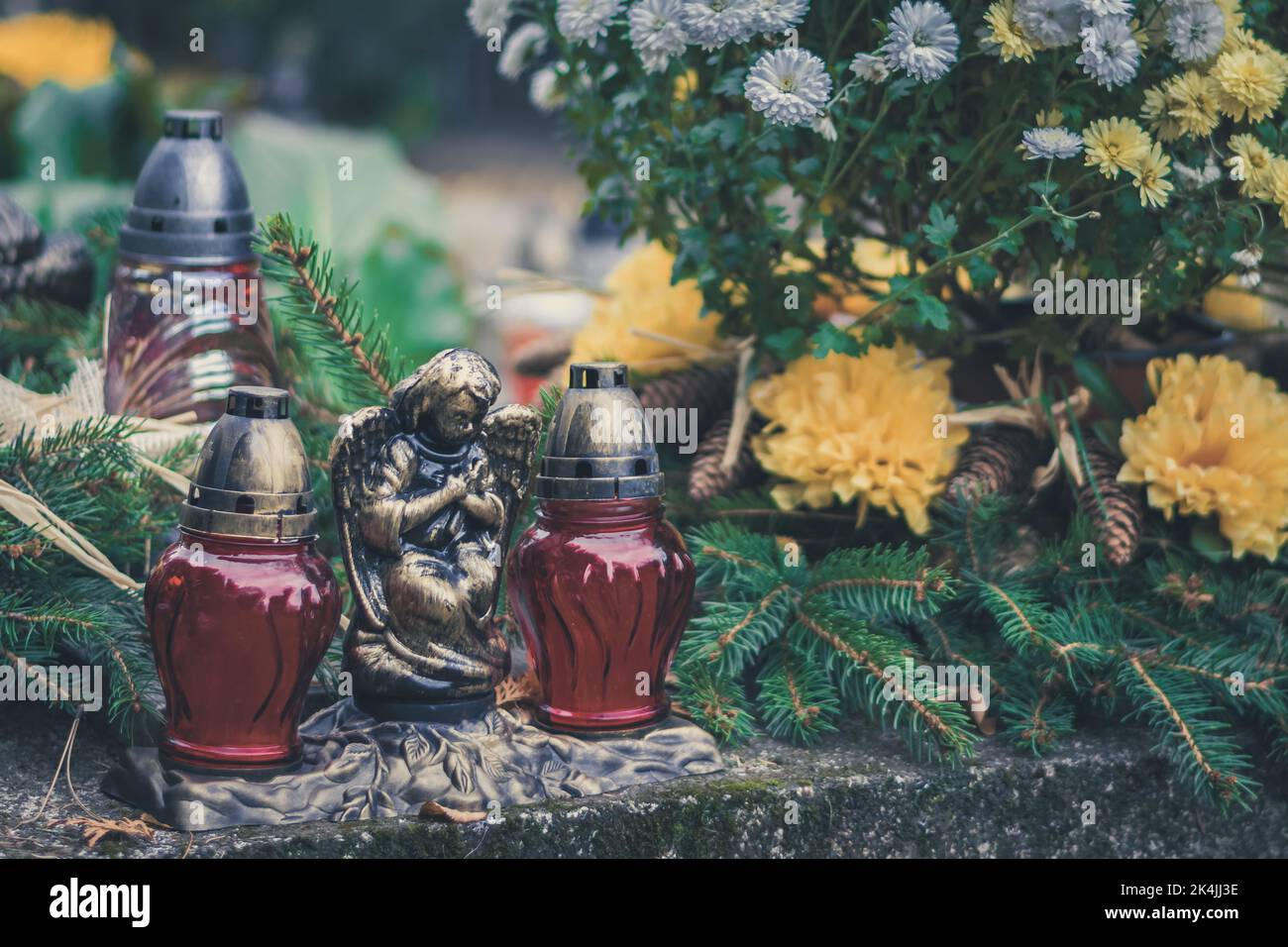 burning candle and floral decoration on grave in the cemetery Stock ...