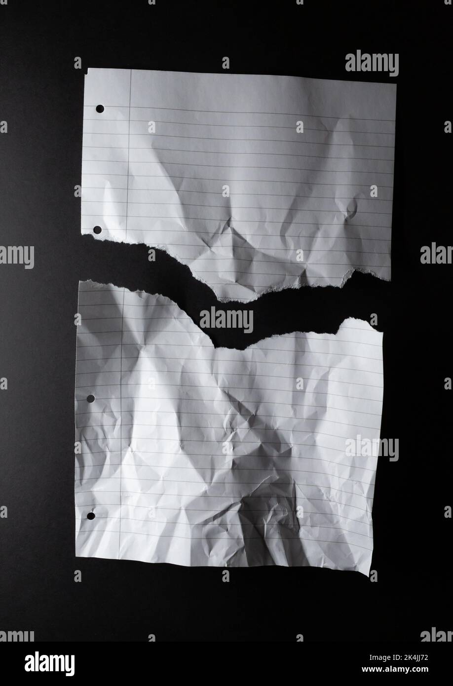 Two halves of scrunched up, hole punched sheet of lined white notebook ...