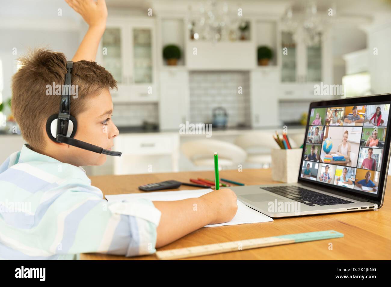 Caucasian boy raising hand for video call, with smiling diverse ...
