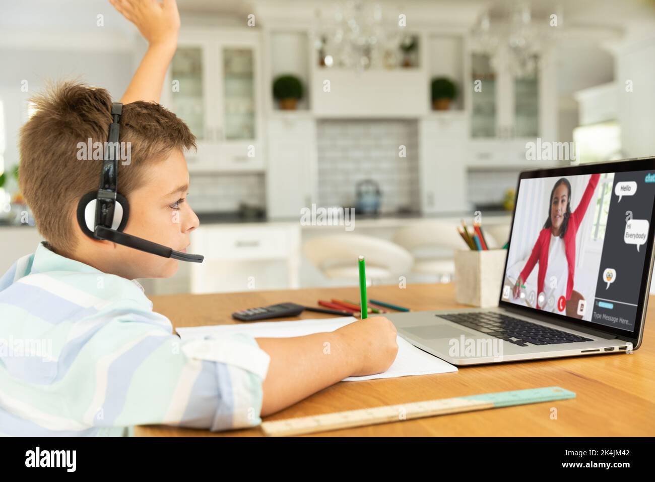 Caucasian boy raising hand for video call, with elementary school pupil ...